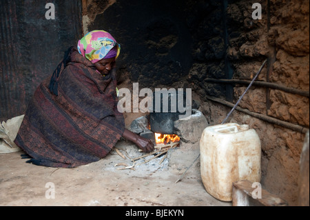 Woman cooking over an open fire in her basic rural village kitchen, The ...