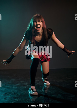 Full length portrait of a punk girl making a rock hand gesture isolated ...