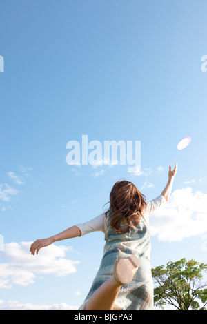 Woman with arms raised throwing plastic bottles in front of building ...