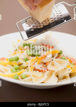 Hand grating cheese with a cheese grater onto a plate Stock Photo - Alamy