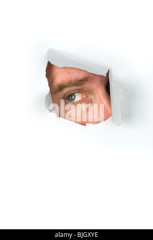 Man peeking through torn white surface Stock Photo - Alamy