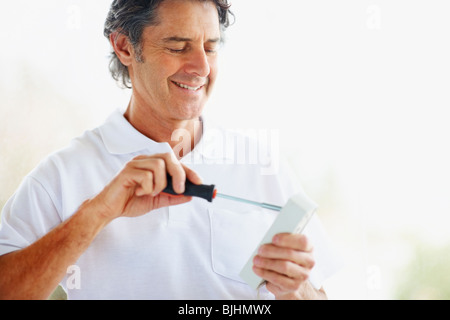 mature man using electric screwdriver while making bookcase Stock Photo ...