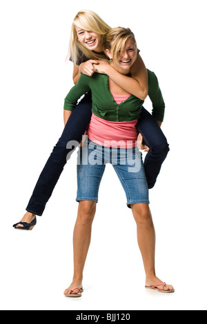 Teenage girl giving her sister piggyback ride in garden Stock Photo ...