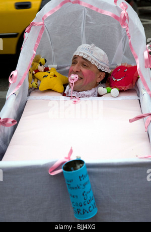 A street performer or busker dressed as a baby in a pram in Bologna ...