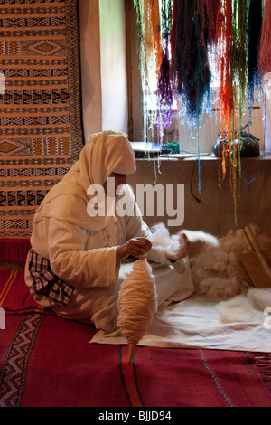 Berber woman sitting on the floor grinding argan kernels to pulp for ...