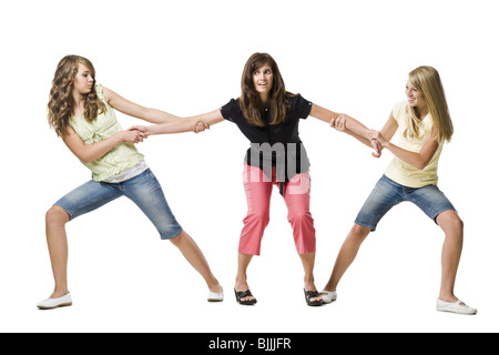 Two girls pulling mother's arms in both directions Stock Photo - Alamy