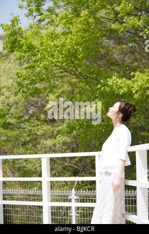 Japanese woman leaning against a railing with a city in the background ...