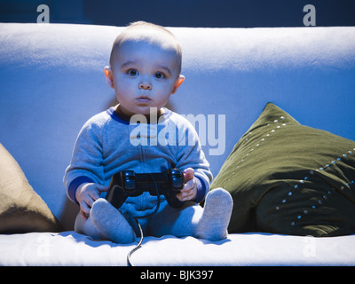 Baby on sofa with video game controller Stock Photo - Alamy