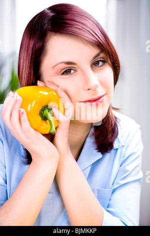 A person holds a yellow bell pepper in their hand. The garden is full ...