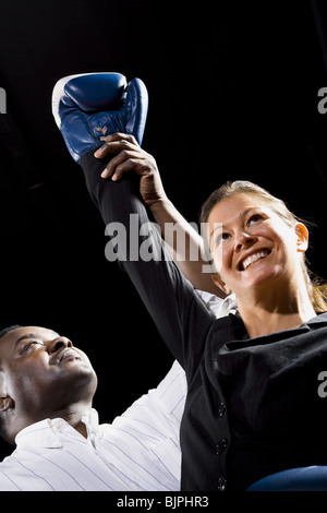 Male referee looking at female boxer punching competitor in boxing ring ...