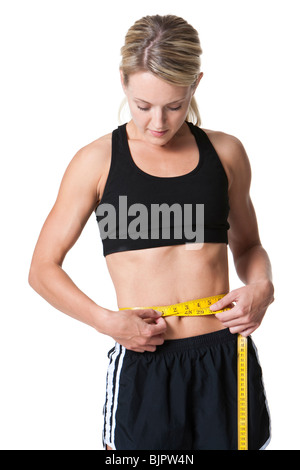 slender young female model measures her waist with a tape measure with ...