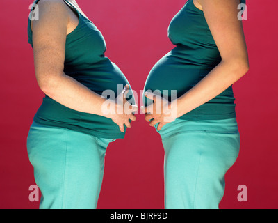 cropped view of two pregnant women showing bellies in profile isolated ...