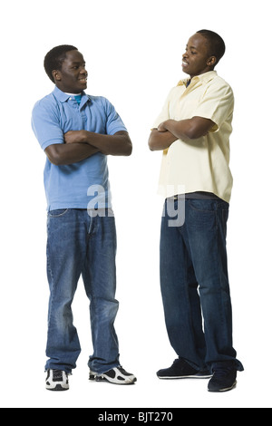 Young brothers posing with crossed arms on light blue background. Space ...
