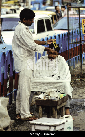 Indian barber cutting hair outside on the ghats by the Ganges in ...