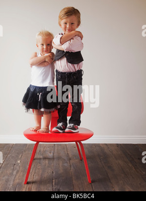 Young girl standing on chair to reach book on bookshelf Stock Photo ...