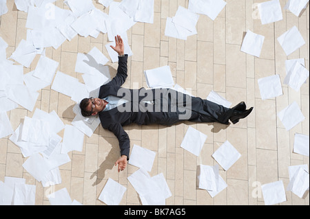 Businessman lying on floor with scattered papers Stock Photo - Alamy
