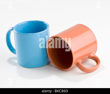 A blue coffee cup is tipped over with beans spilling out of the cup ...