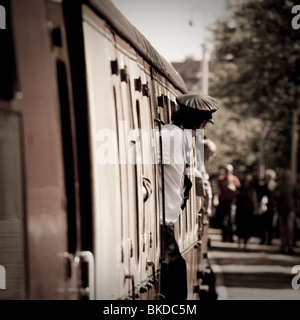 Steam train conductor leaning out of passenger car window Stock Photo ...
