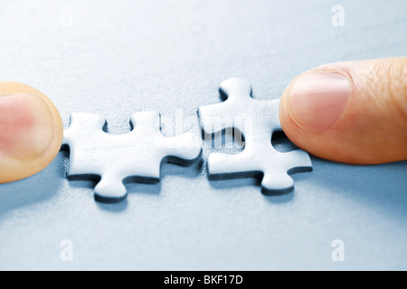 Fingers pushing two matching puzzle pieces together Stock Photo - Alamy