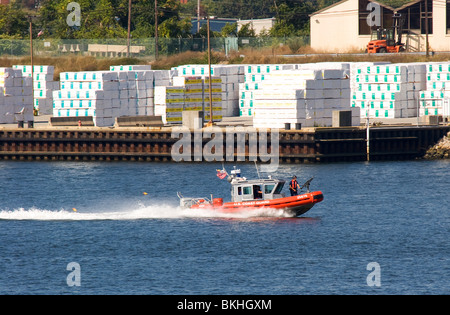 A US Coast Guard rigid hull inflatable escort boat speeds past a ...