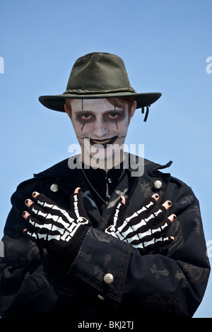 Sinister man with Halloween skeleton makeup slowly appears from dark ...