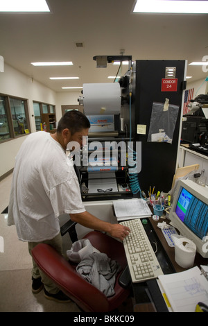 Inmate working at license plate manufacturing computer and printer at ...