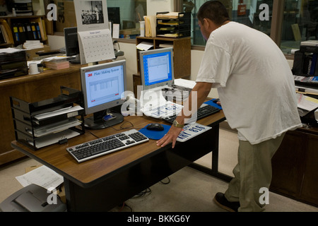 Inmate working at license plate manufacturing computer and printer at ...