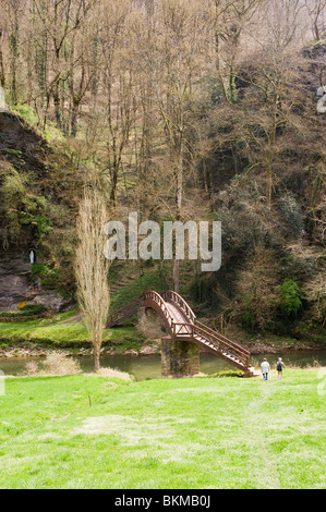Two walkers crossing footbridge over Afon Cwm Llan river waterfall in ...