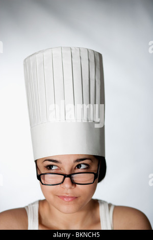 Young serious chef in eyeglasses standing in uniform in kitchen and ...