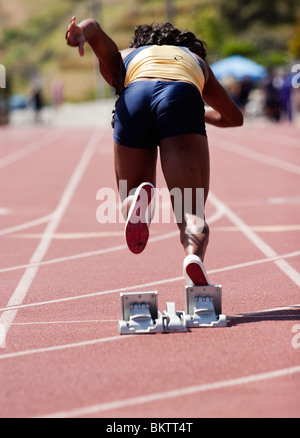 Female sprinter leaving starting blocks on running track in stadium ...