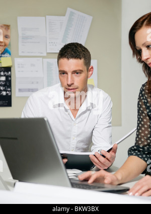 Two people at desk look at computer Stock Photo - Alamy