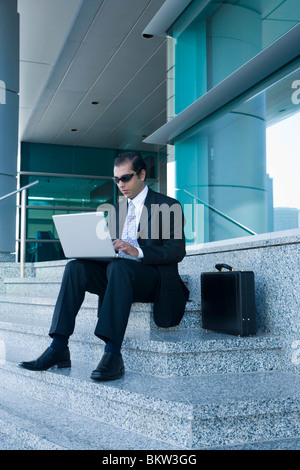 Low angle view of businessman using phone against modern buildings in ...