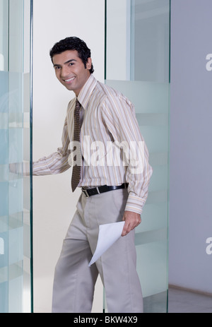 Businessman entering a room, holding a document Stock Photo - Alamy