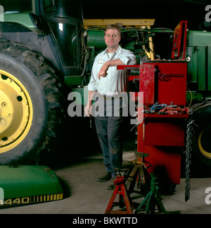 Portrait of farm equipment mechanic in his shop surrounded by tractors ...