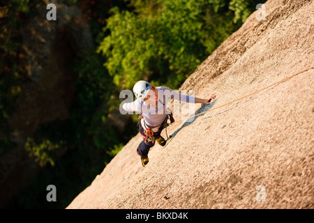 Woman climbing near top of a steep set of outdoor wooden stairs ...
