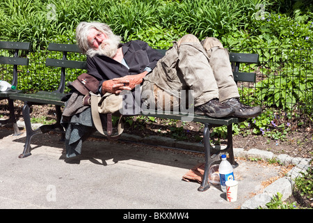 Homeless man in ragged clothes eating a meal standing as his benefactor ...