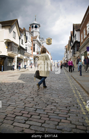 People walk along a street with high old stone walls with doorways as ...