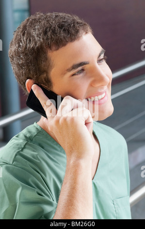 Nurse smiling while talking on a mobile phone inside a car before or ...