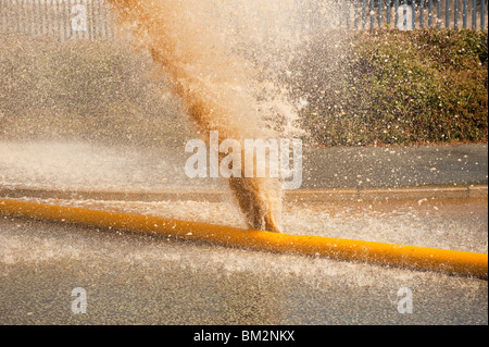 High Volume fire hose burst with water pouring out of leak Stock Photo ...