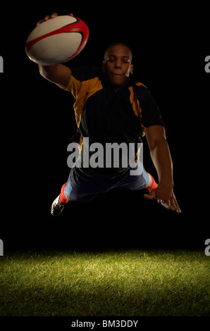 Rugby player jumping with the ball to score touchdown in sports stadium ...
