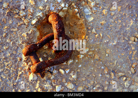 old rusted shackle on the harbor concrete stones, golden sunset light ...