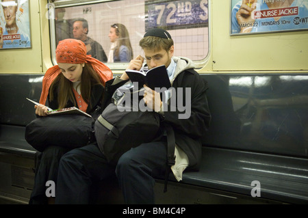 Commuters, standing, reading books on the subway in New York, on Sunday ...