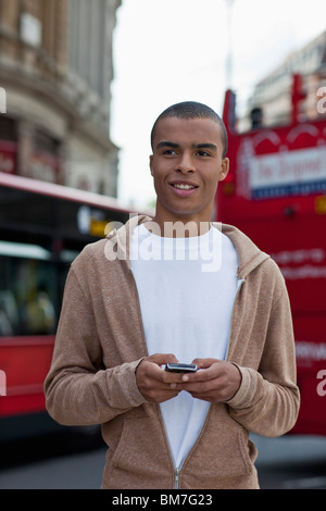 Young man text messaging on mobile phone while using laptop Stock Photo ...