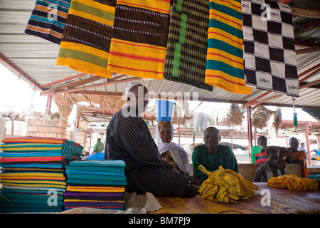 A Fulani man sells strips of cloth woven together into colorfully ...