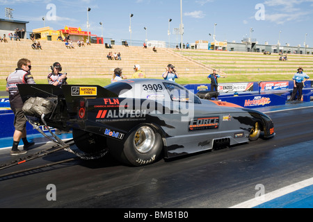 A sleek and streamlined drag racing car approaches the start line at ...