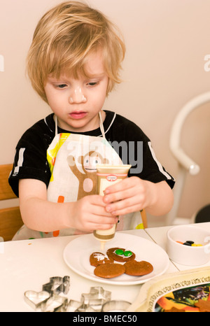 The boy is holding a gingerbread cookie in the shape of a snowman ...