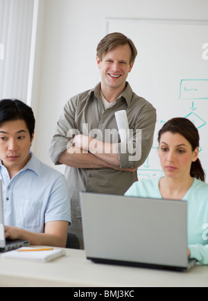Female mentor teacher working with male teenage high school students in ...