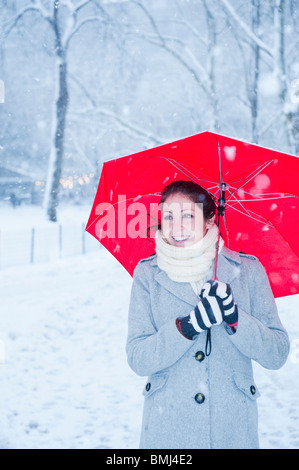 A happy woman walks with a red umbrella in her hands, a winter park ...