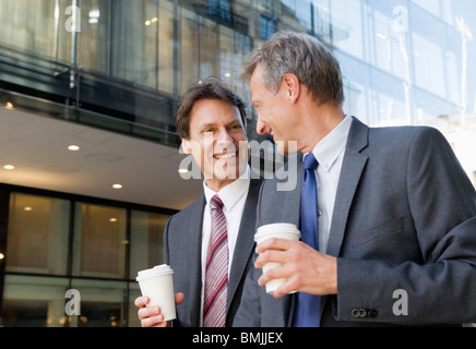 A man walks with two cups of coffee past solar panels set up on the ...