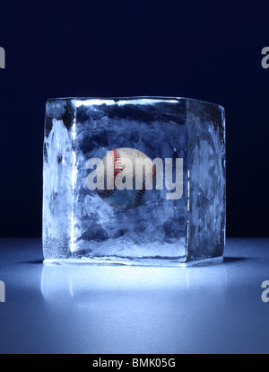A frozen block of ice with a baseball frozen inside on a metal surface ...